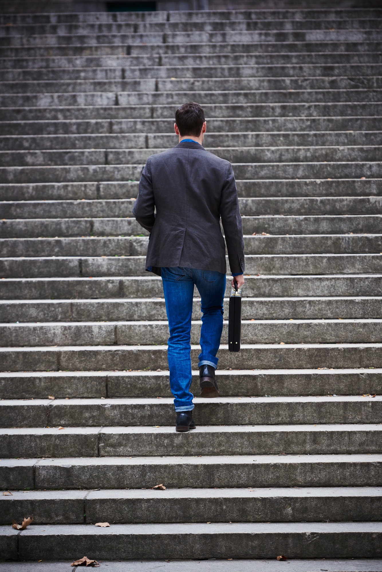 A young man walking up on a flight of steps holding a briefcase, seen ...